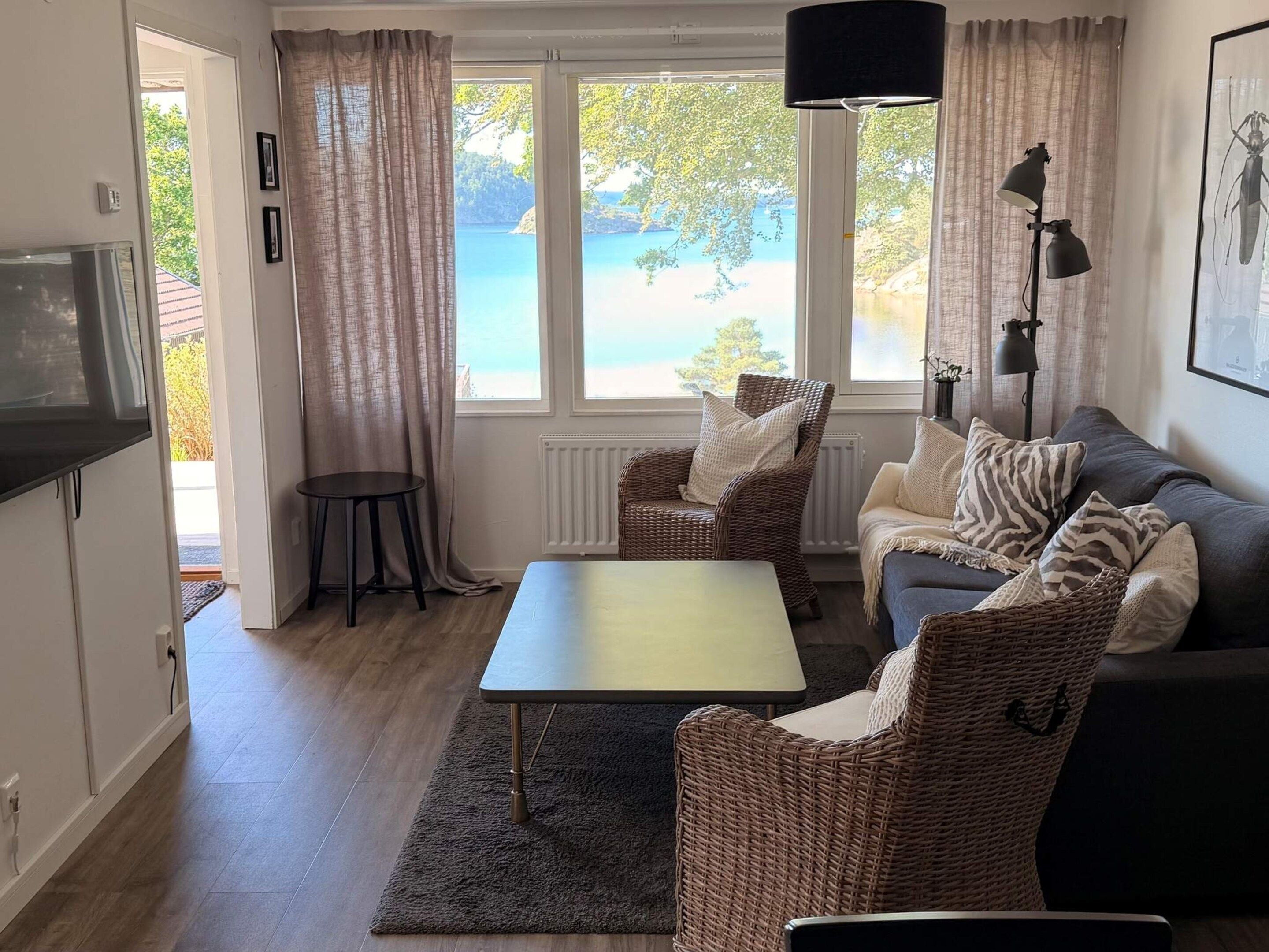 Sala de estar com vista para um lago, um sofá, uma mesa e um abajur.