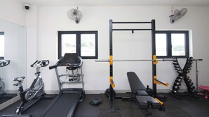 Uma academia com equipamentos de ginástica, incluindo esteira, elíptico e área de musculação.