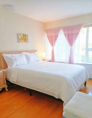Quarto com uma cama grande, mesa de cabeceira, abajur e janela com cortinas.