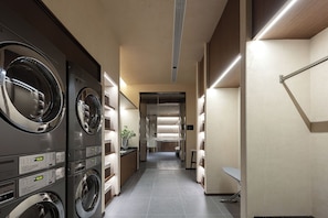 A laundry room with multiple washing machines, a sink, and a plant.