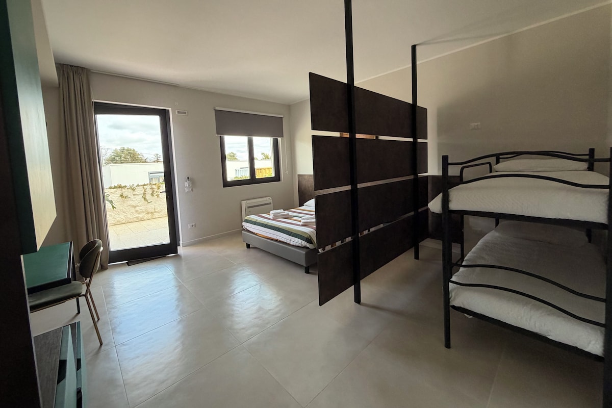 Quarto com beliche, escrivaninha com cadeira, radiador e janela com vista para o exterior.
