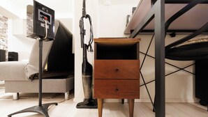 Quarto compacto com uma cama, uma escrivaninha e um pequeno armário de madeira.