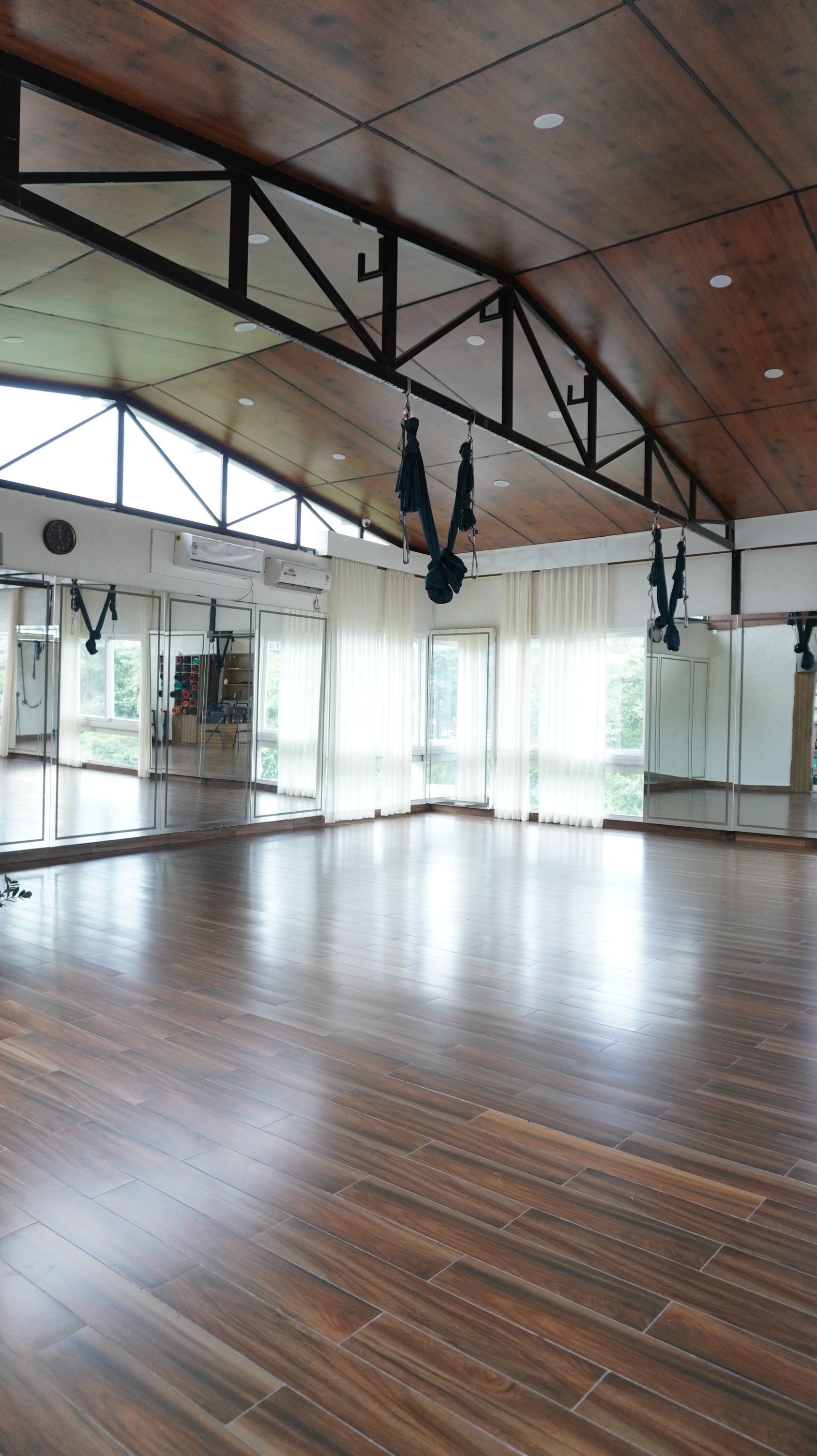 Quarto espaçoso com teto alto, janelas amplas e piso de madeira.