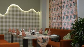 Restaurante com paredes quadriculadas, tapeçaria estampada e assentos estofados em laranja.