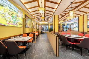 Interior de restaurante com vigas de madeira, cadeiras laranja e piso de mármore.