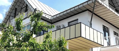 Um edifício moderno com telhado inclinado, janelas grandes e uma varanda.