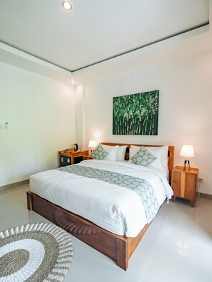 Um quarto com uma cama grande, uma mesinha de cabeceira, uma luminária na parede e uma pintura de árvores.