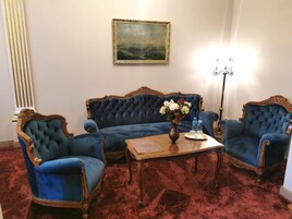 Um quarto com um sofá azul estofado, uma mesa de centro de madeira e um vaso com flores.