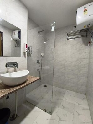 Uma casa de banho moderna com chuveiro em cabine de vidro, pia branca e soalho em mármore.