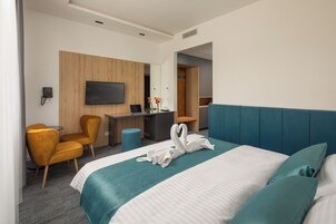 Quarto de hotel com uma cama, uma escrivaninha, uma cadeira, uma televisão e um espelho.