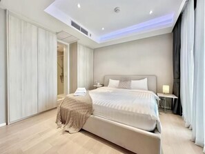 Um quarto moderno com uma cama grande, mesas de cabeceira e um closet espaçoso.