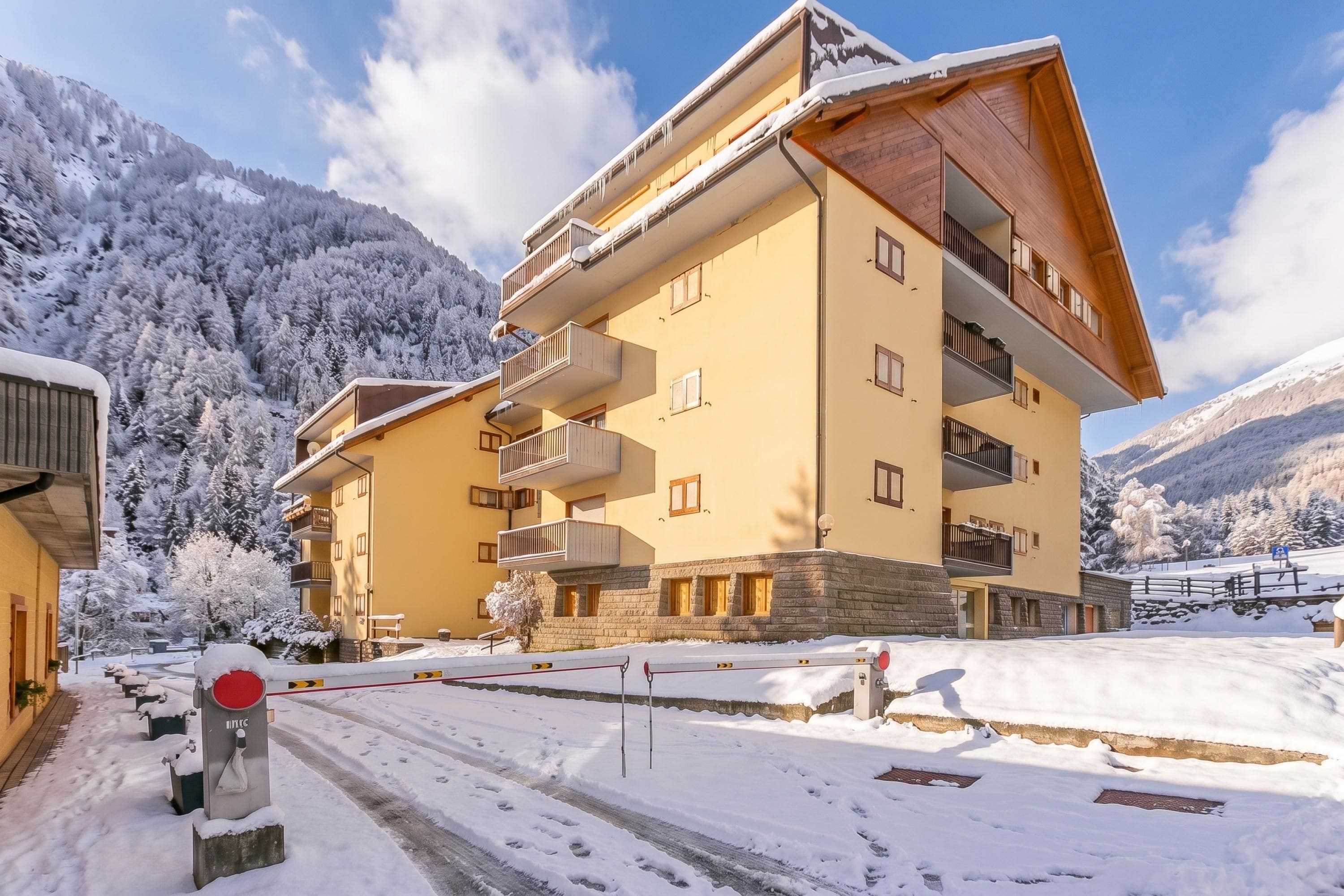 Hotel com vários andares e varandas, com montanhas nevadas ao fundo.