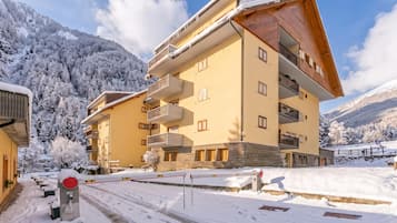 Hotel com vários andares e varandas, com montanhas nevadas ao fundo.