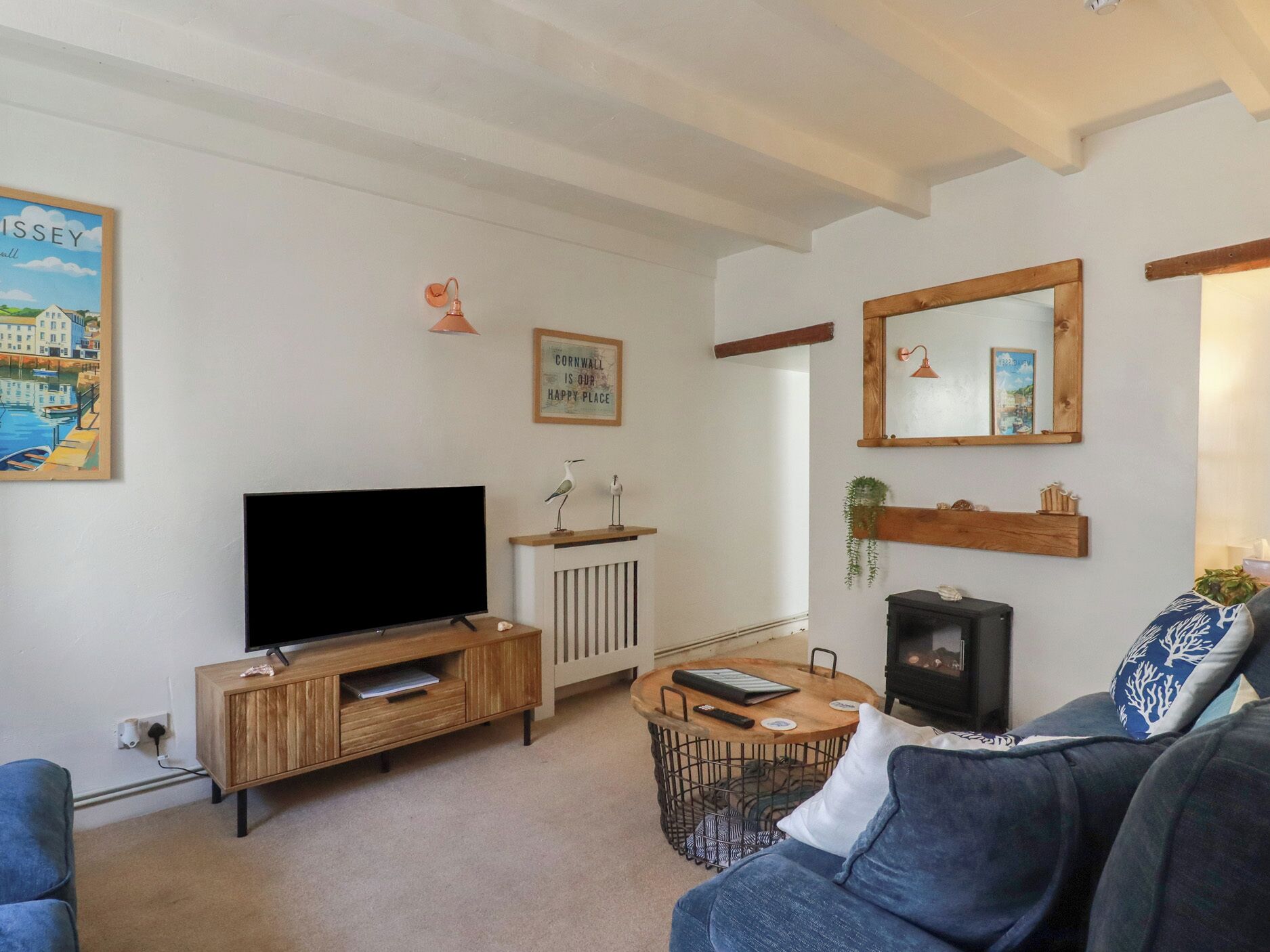 Uma sala de estar com televisão, móveis de madeira, um sofá, uma mesinha e uma lareira.