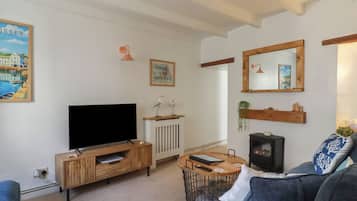Uma sala de estar com televisão, móveis de madeira, um sofá, uma mesinha e uma lareira.