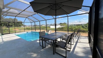 Uma área externa coberta com piscina, assentos e vista para a paisagem ao redor.