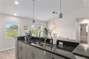Uma cozinha moderna com bancadas de granito, eletrodomésticos de aço inoxidável e uma janela grande com persianas.