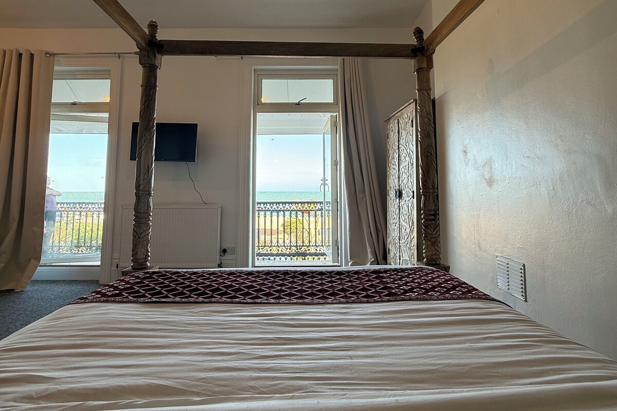Quarto com cama grande, luminária no teto, janela com cortinas e vista para o exterior.