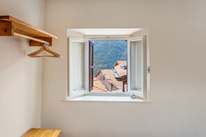 Um quarto com uma pequena janela, um cabide de madeira e uma mesa de madeira.
