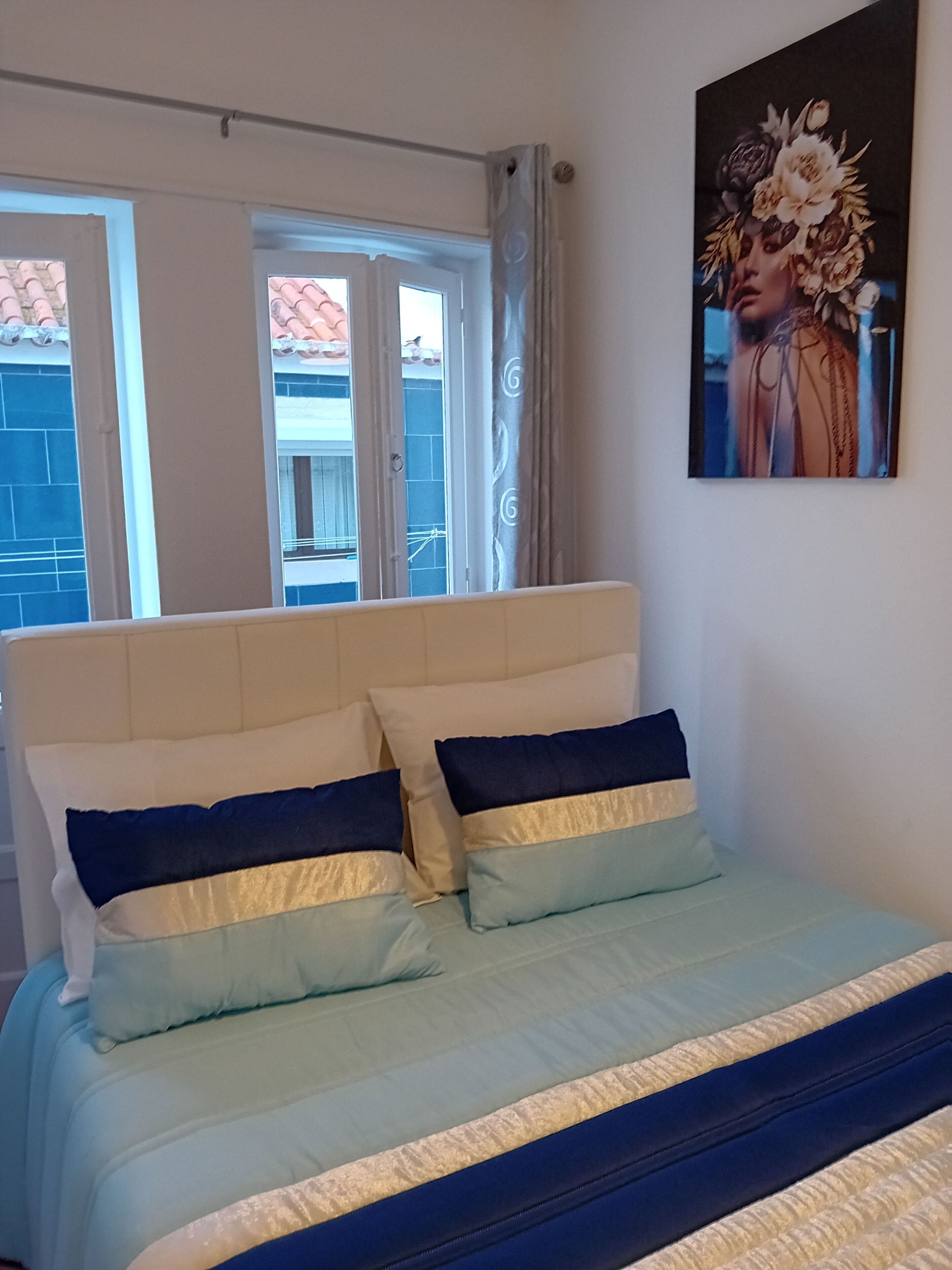 Uma cama com cabeceira, almofadas e um quadro na parede.