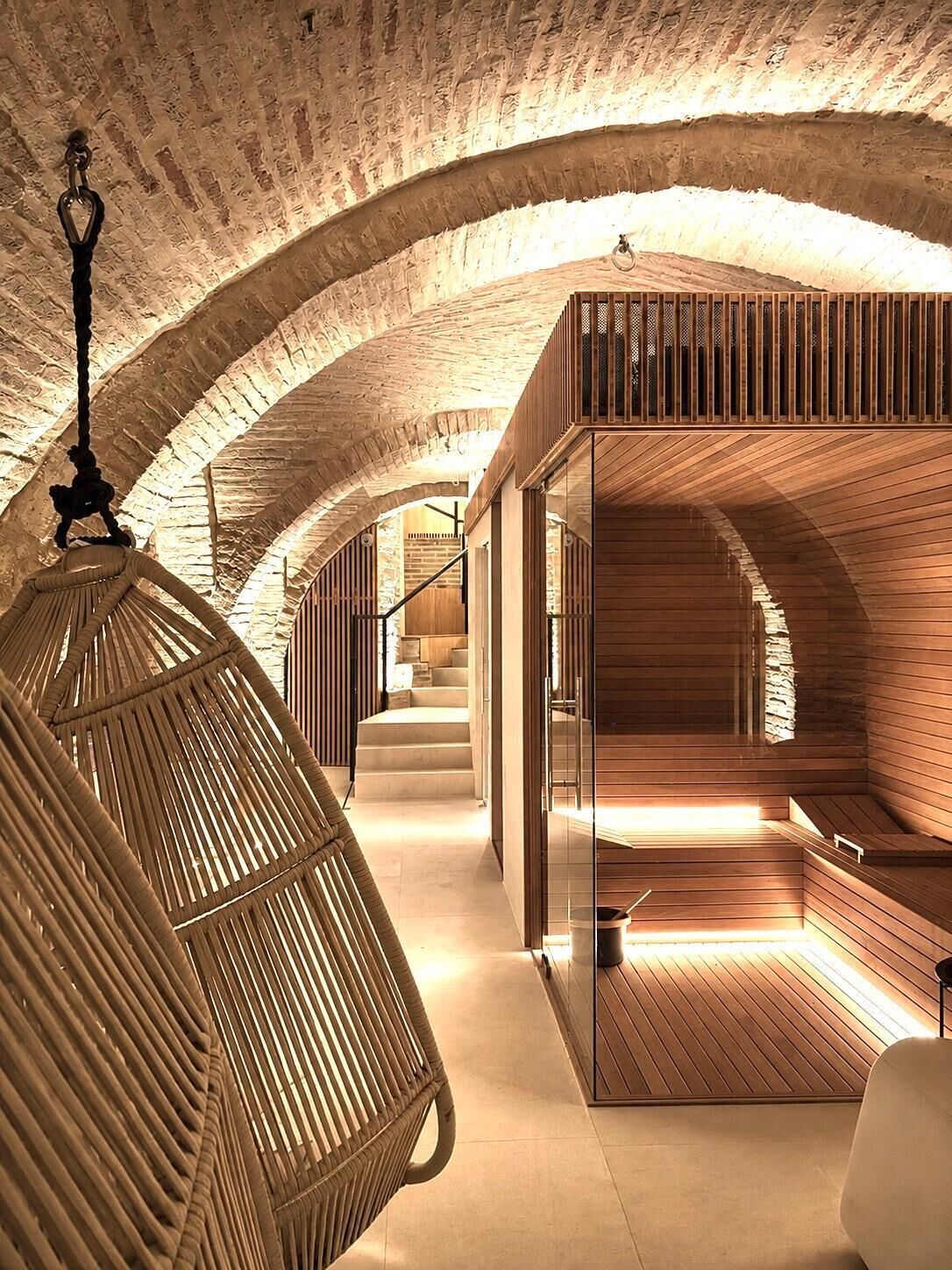 Uma área de spa com um banco de madeira, um lustre pendurado e uma escada que leva a outro nível.