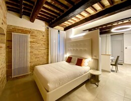 Um quarto com uma cama grande, uma mesa de cabeceira, um radiador e teto de madeira.