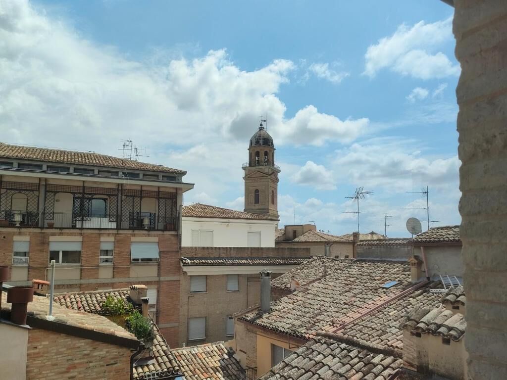 Um edifício com uma torre de sino, telhas de barro e céu claro.