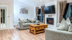 Uma sala de estar com sofá, mesa de centro, lareira e televisão fixada na parede.