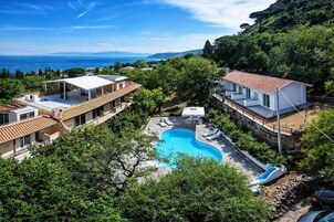 Um imóvel residencial com piscina, várias varandas e vista para o mar.