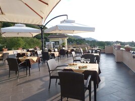 An outdoor patio with tables and chairs, umbrellas, and potted plants.