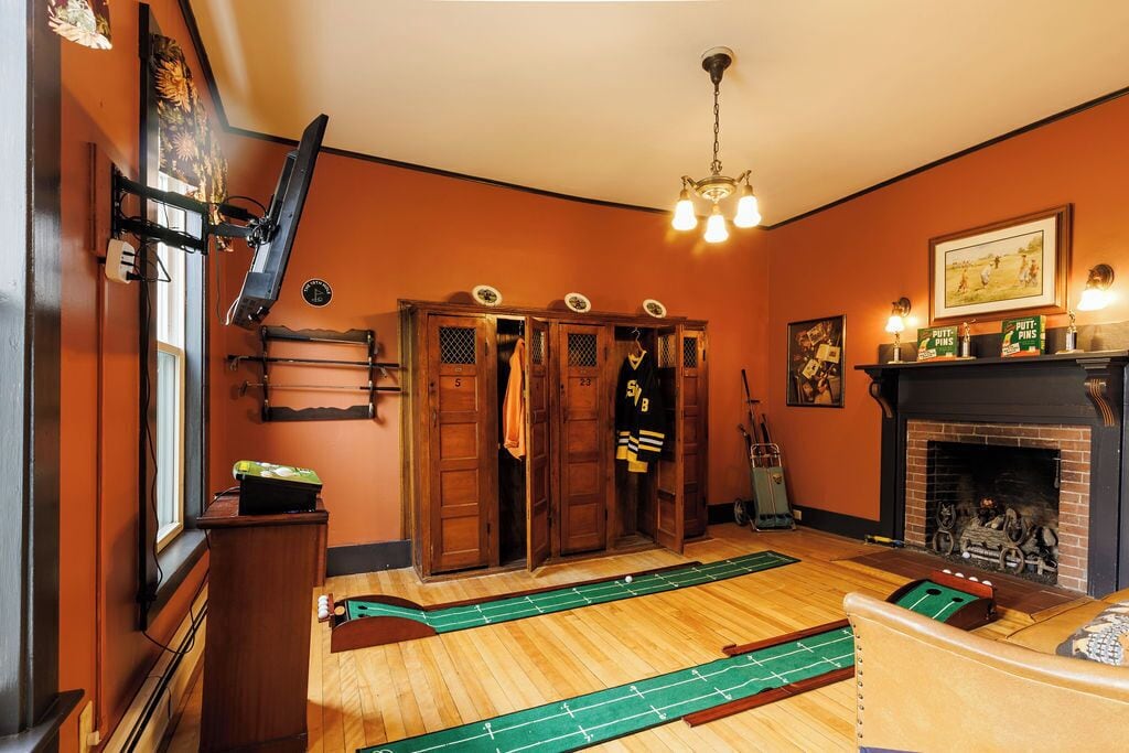 Um quarto com mesa de bilhar, lareira e um conjunto de portas de madeira.