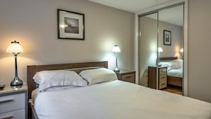 Quarto de hotel com cama, abajures, mesa de cabeceira, cômoda e espelho.