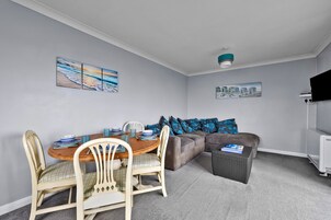 Um quarto com uma mesa de jantar, cadeiras, um sofá e uma televisão.