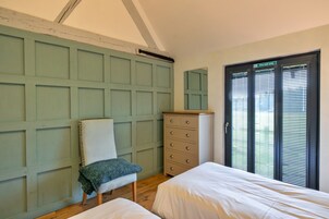 Quarto com cama, uma cadeira, cômoda e porta com sinalização de saída de incêndio.