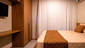 Quarto de hotel com cama, televisão na parede, guarda-roupa e ar condicionado.