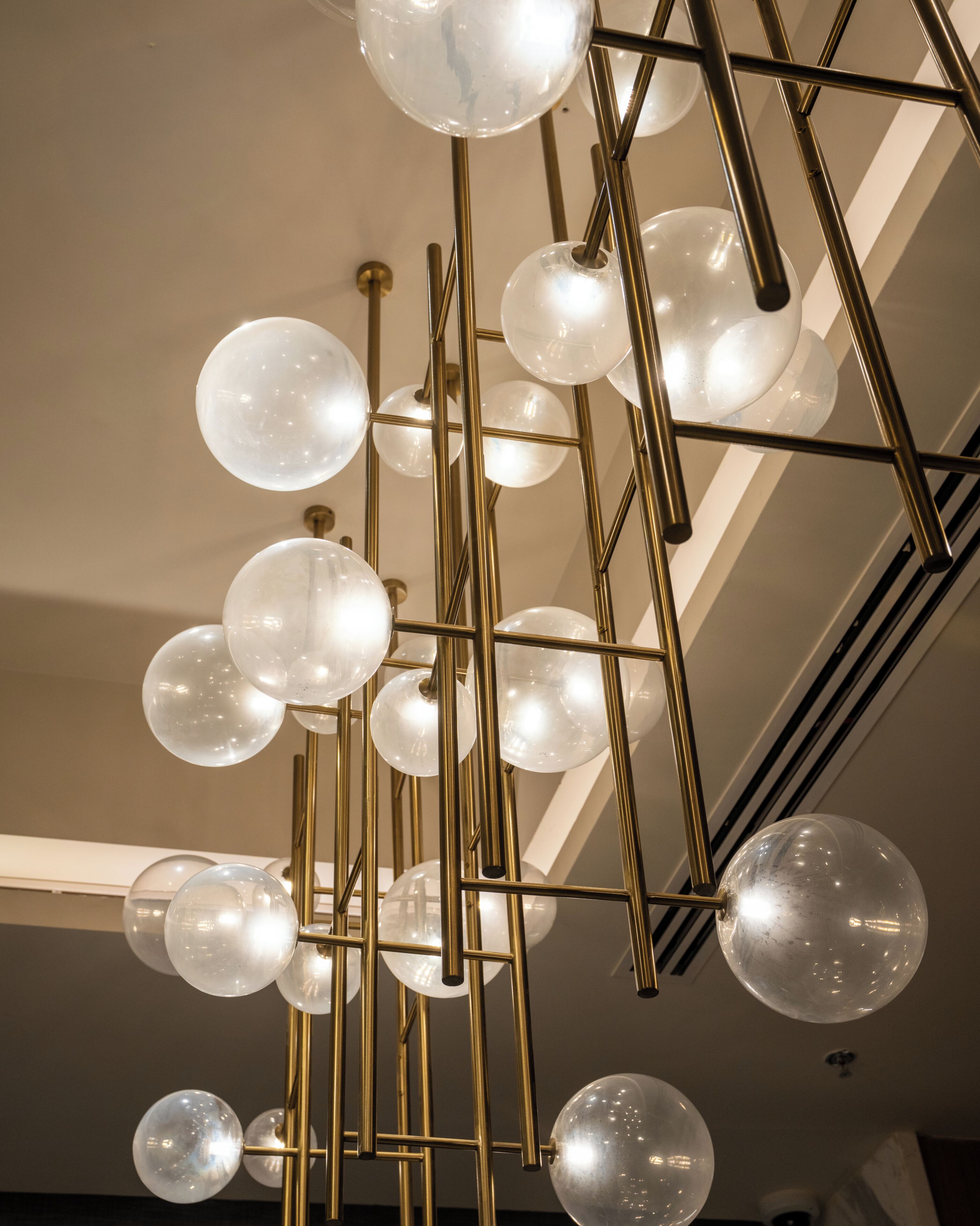 Um lustre moderno com várias cúpulas esféricas de vidro e estrutura de metal dourado.