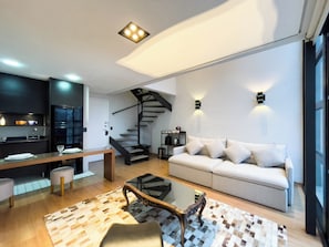 Um espaço moderno de estar com escadas, uma área de jantar e um sofá.