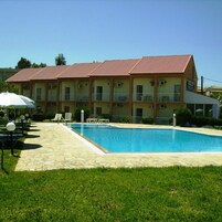 Um hotel com piscina, área de estar externa e telhado com telhas vermelhas.