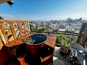 Terraço no telhado com deck de madeira, banheira de hidromassagem e vista para o horizonte urbano.