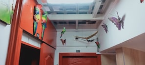 Um corredor com uma porta vermelha, número 301, e teto decorado com borboletas penduradas.