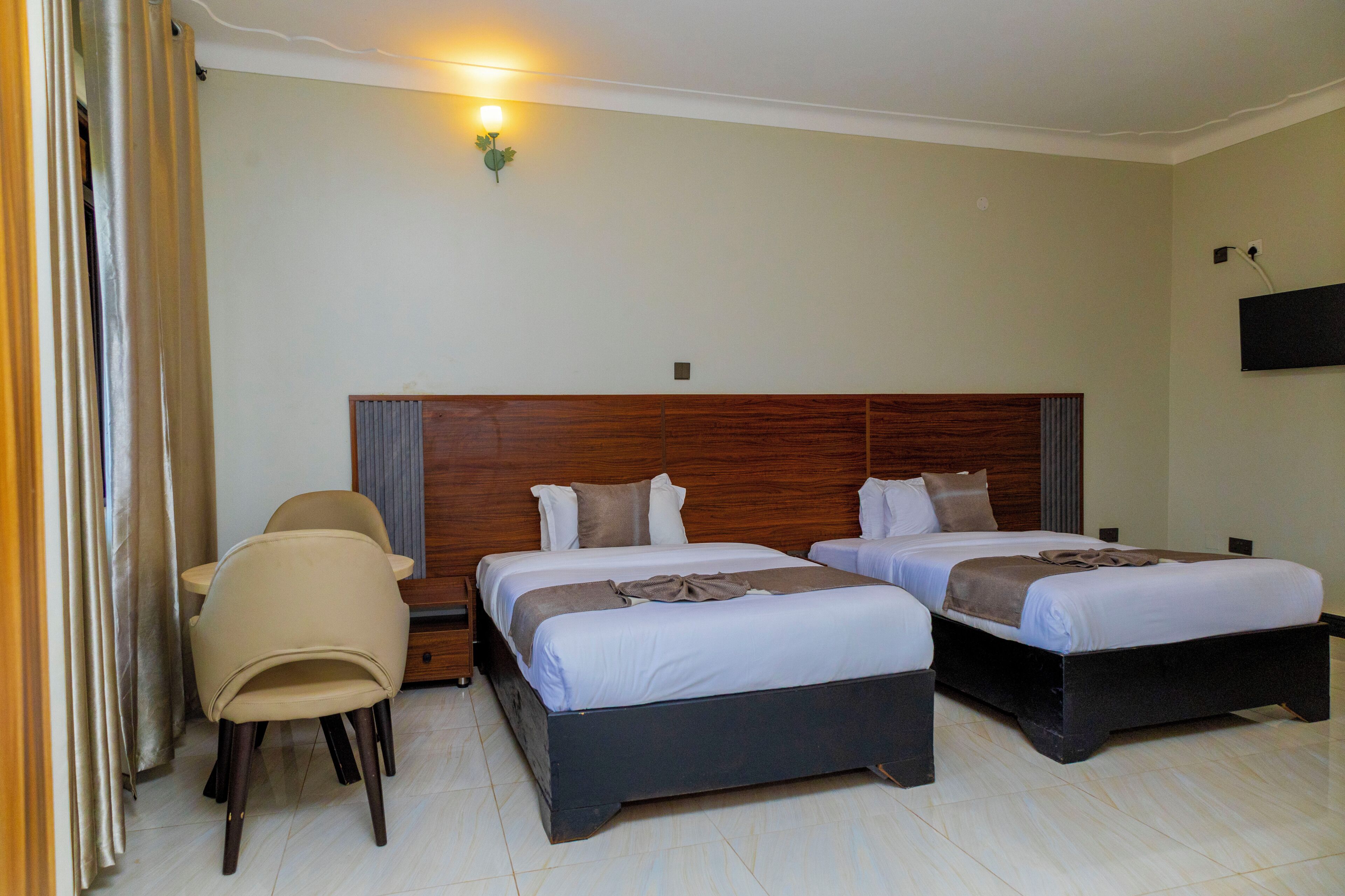 Quarto de hotel com duas camas, uma escrivaninha e uma cadeira.