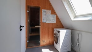 A laundry room with a washing machine, a door with a glass panel, and a skylight.