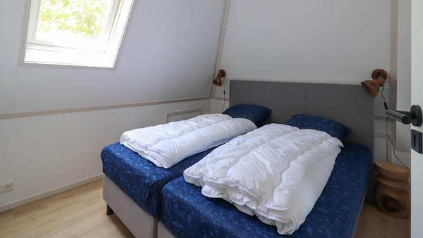 A bedroom with two beds, a window, and a door.
