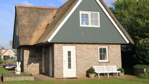 A house with a steeply pitched roof, a small front porch, and a white bench.