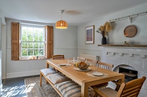 Uma sala de jantar com mesa de madeira, bancos e lareira.