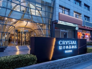 Um edifício moderno com fachada de vidro, uma placa destacada para 'CRYSTAL ORANGE THEATER' e uma entrada bem iluminada.
