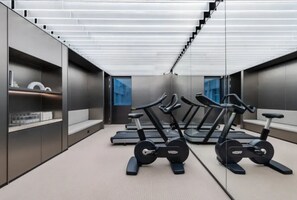 Uma academia moderna com esteiras, um banco de musculação e um espelho grande na parede.