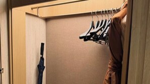 Um closet espaçoso com cabideiro, um par de sapatos e um guarda-chuva dobrado.