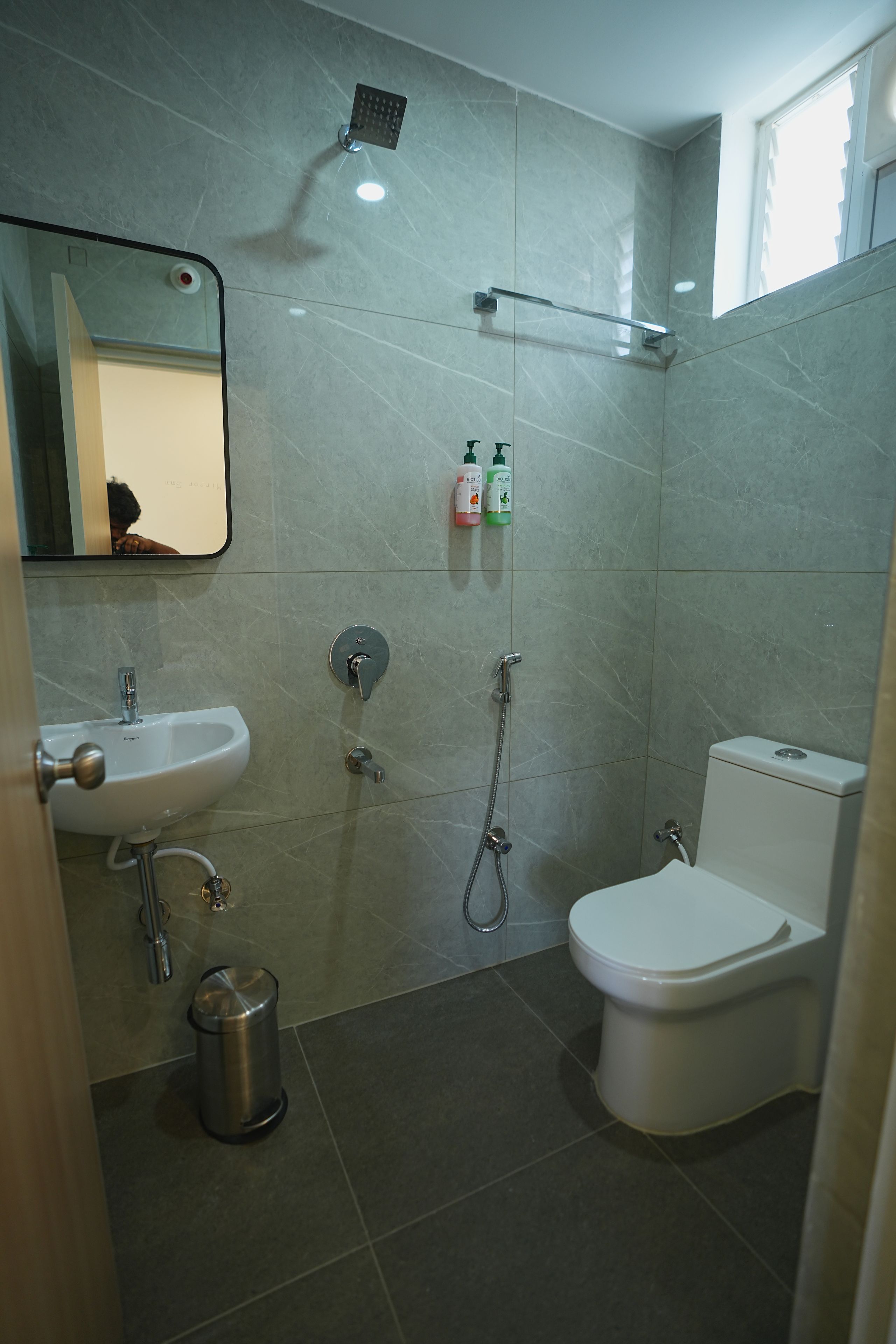 Uma casa de banho moderna com lavatório, sanita, chuveiro e espelho.