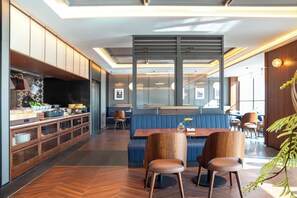 Um restaurante moderno com área de estar central, armários de madeira e estação de preparo de refeições.